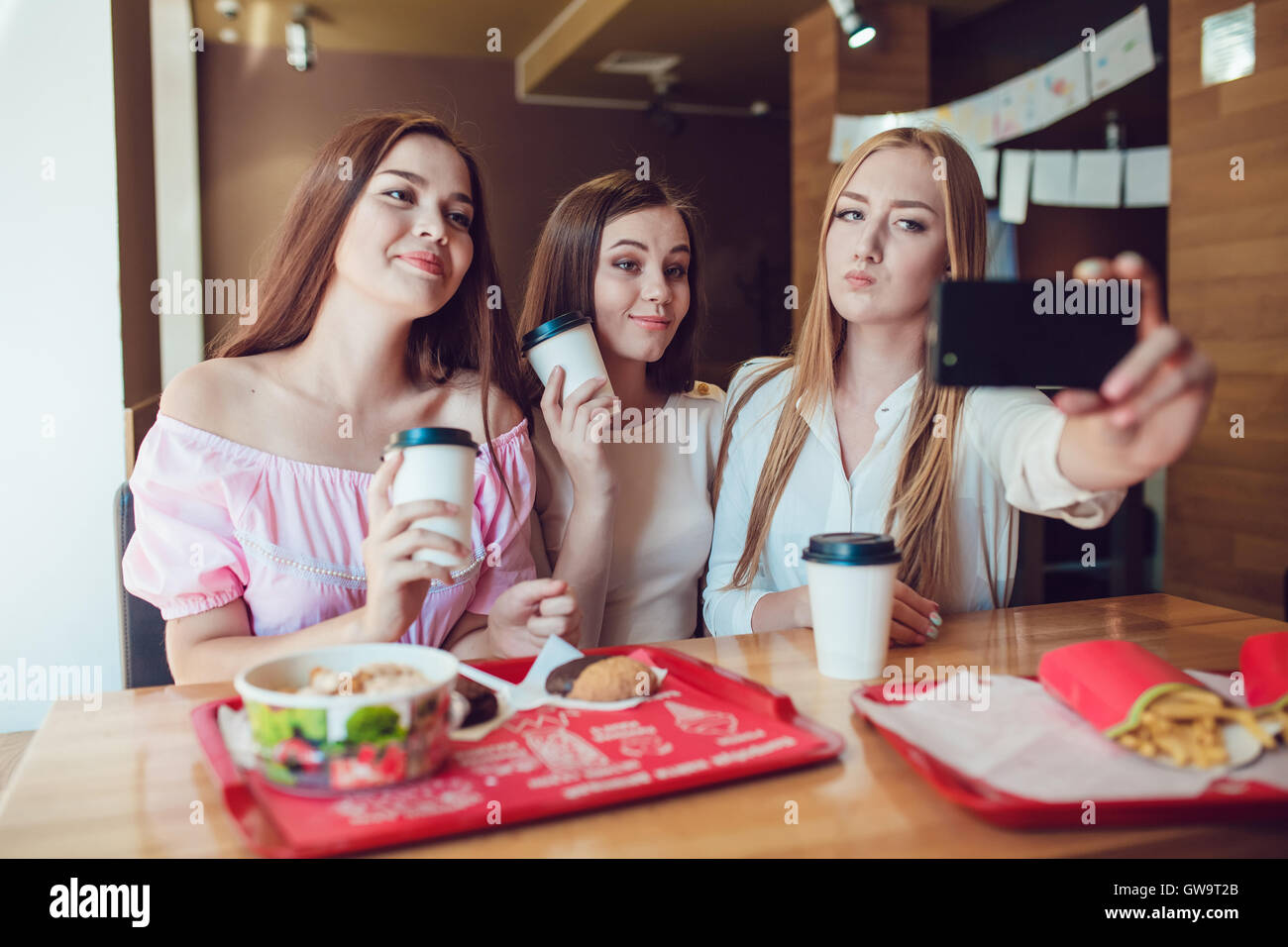 Three young girls are doing selfie in fast food restaurant Stock Photo ...