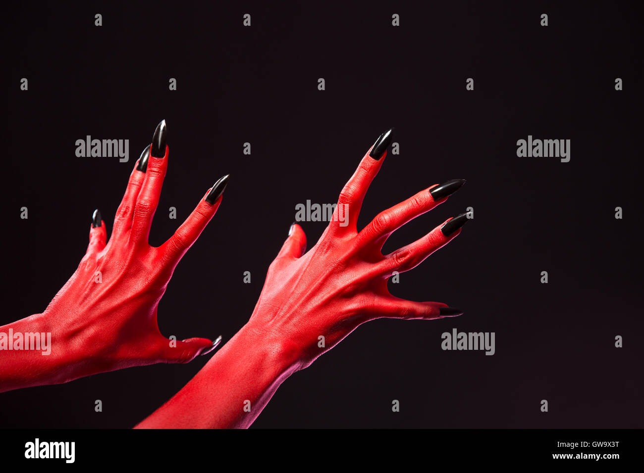 Spooky red devil hands with black nails, real body-art Stock Photo - Alamy