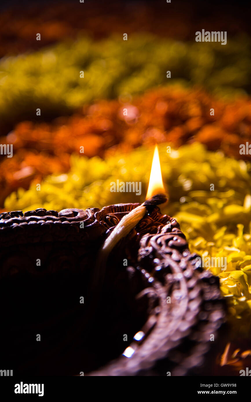 Traditional diya or oil lamp lit on colorful rangoli made up of flower ...