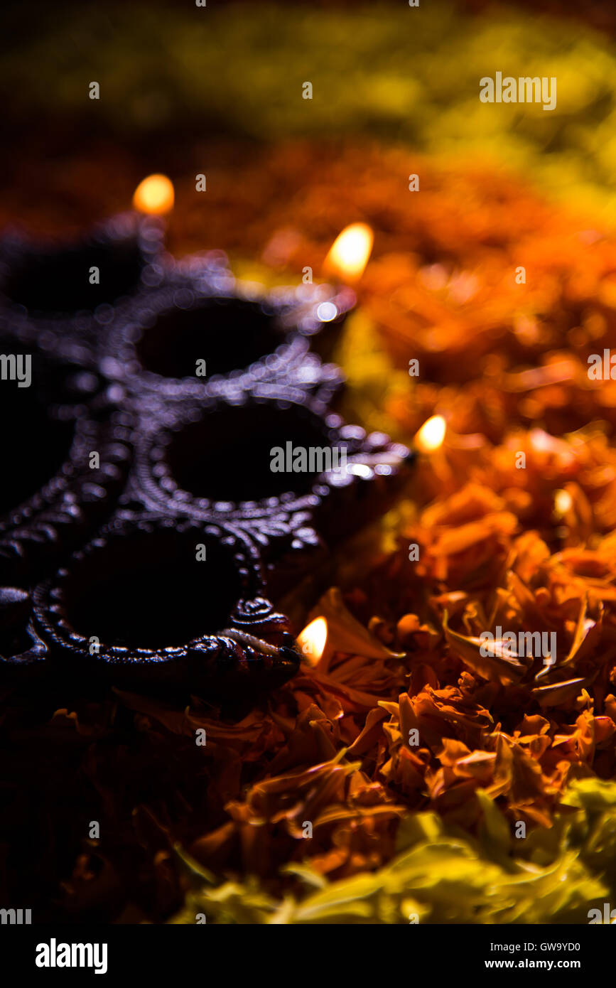 Traditional diya or oil lamp lit on colorful rangoli made up of flower ...