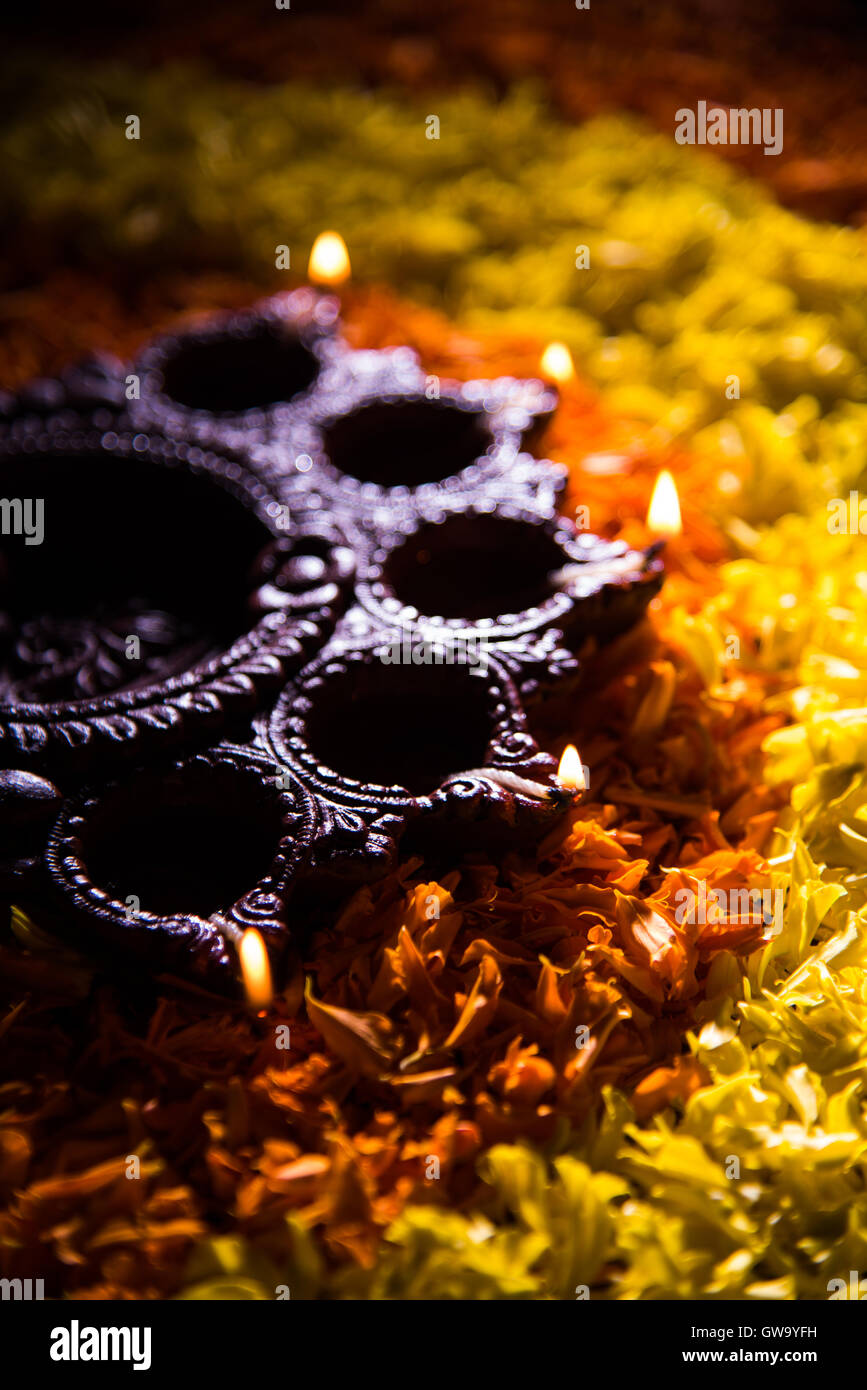 Traditional diya or oil lamp lit on colorful rangoli made up of flower ...