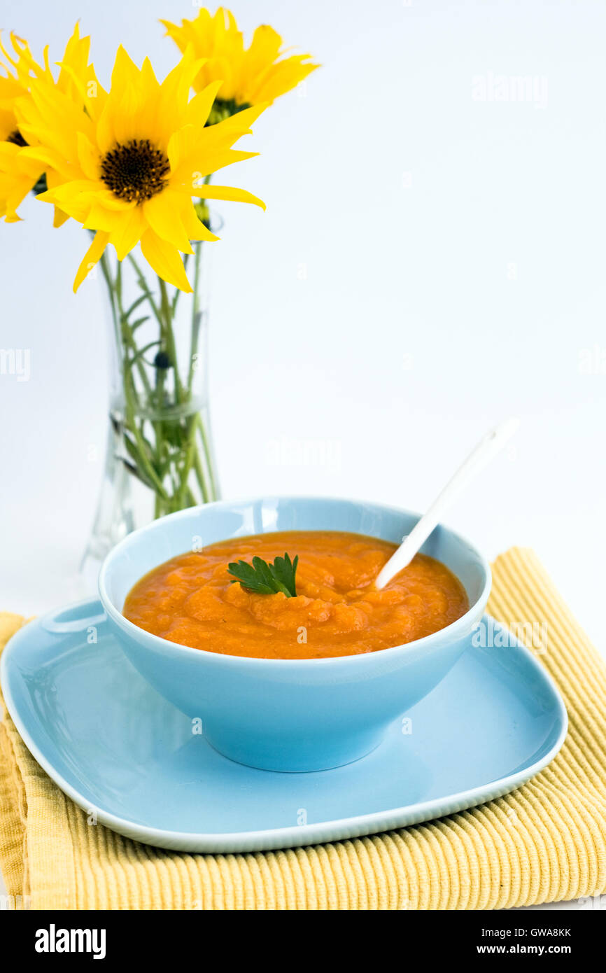 Pumpkin soup in a blue plate and a bouquet of yellow flowers Stock ...