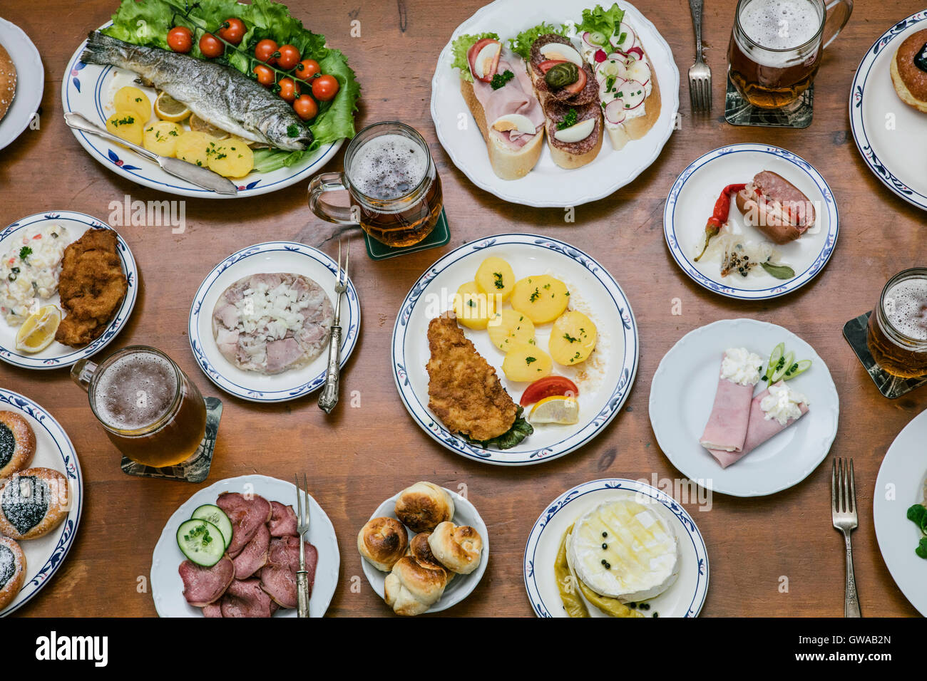 Food from above on a wooden table with young people around eating a ...