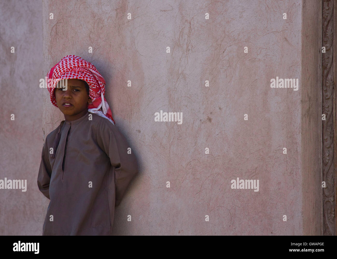 Moqul, Oman, October 22, 2013: A young omani boy standing on a wall. He ...