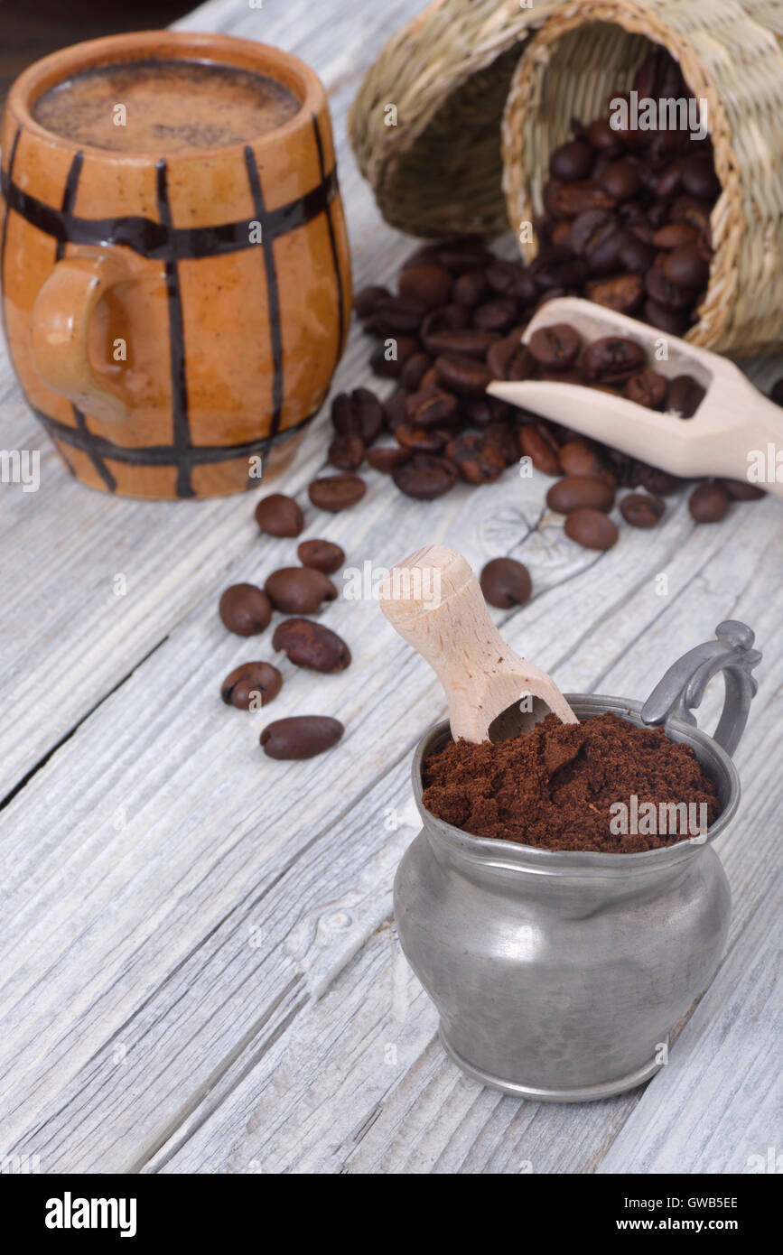 Vintage metal cup with ground coffee on a white wood with coffee beans ...