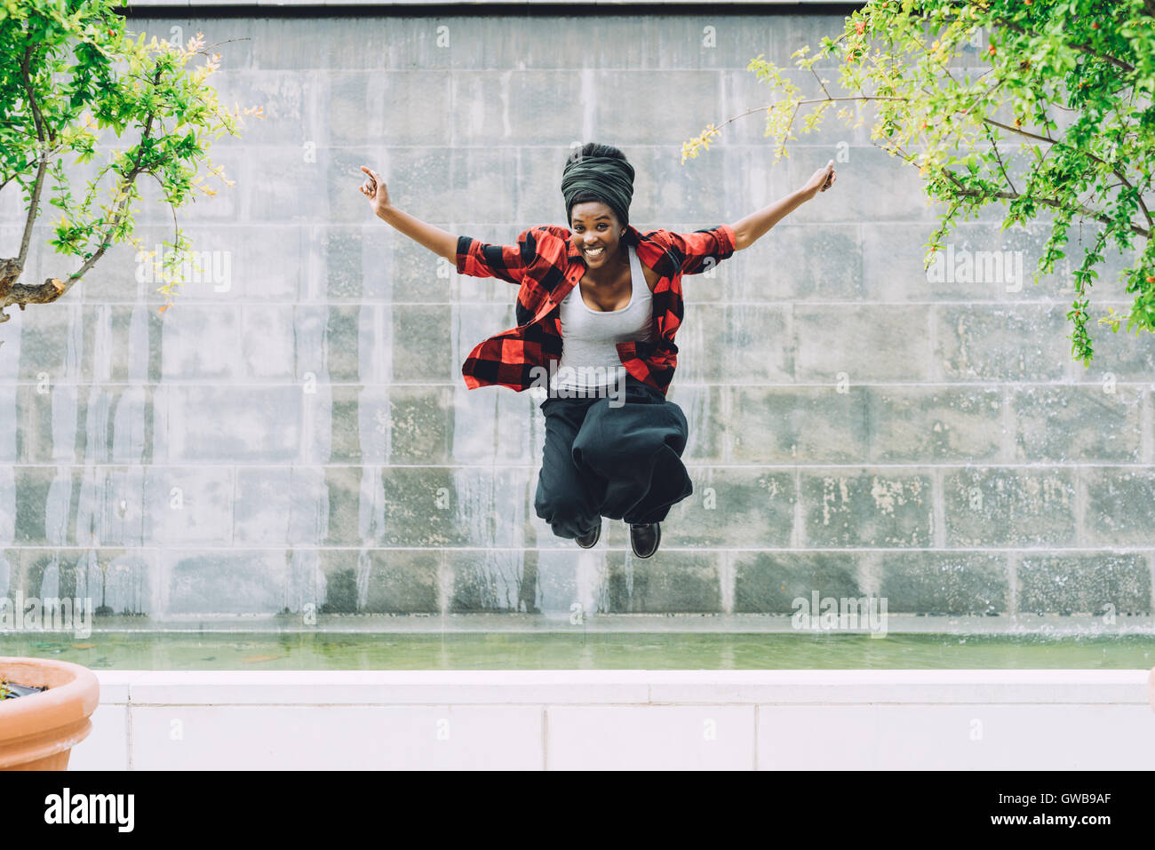 Young beautiful afro black woman jumping in the air outdoor in the city ...