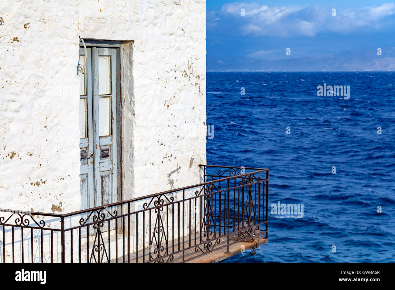 Balcony of a white greek building with the sea and the sky creating a ...