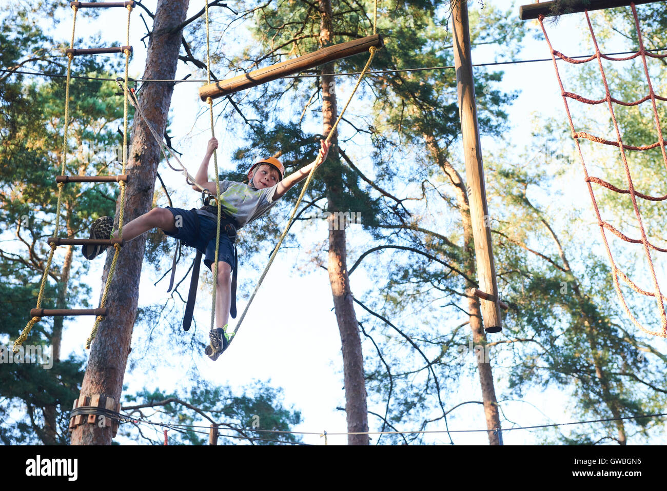 Portrait of active brave boy enjoying outbound climbing at adventure ...