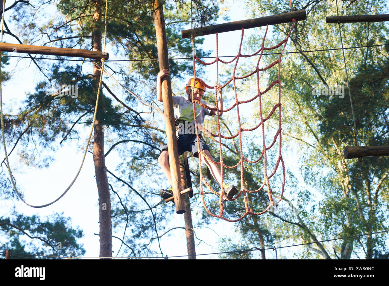 Portrait of active brave boy enjoying outbound climbing at adventure ...