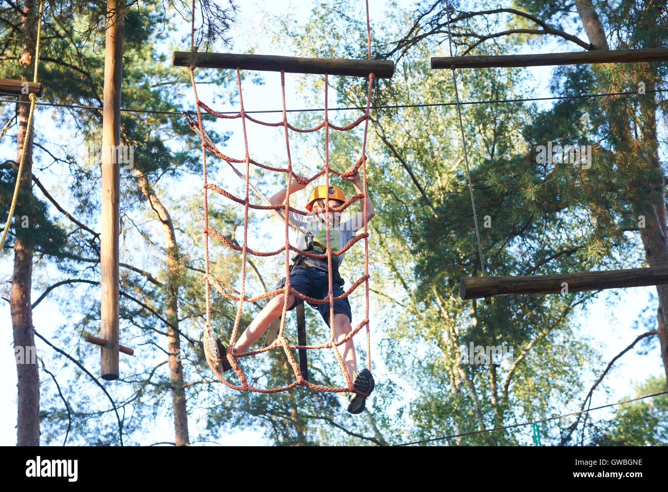Portrait of active brave boy enjoying outbound climbing at adventure ...