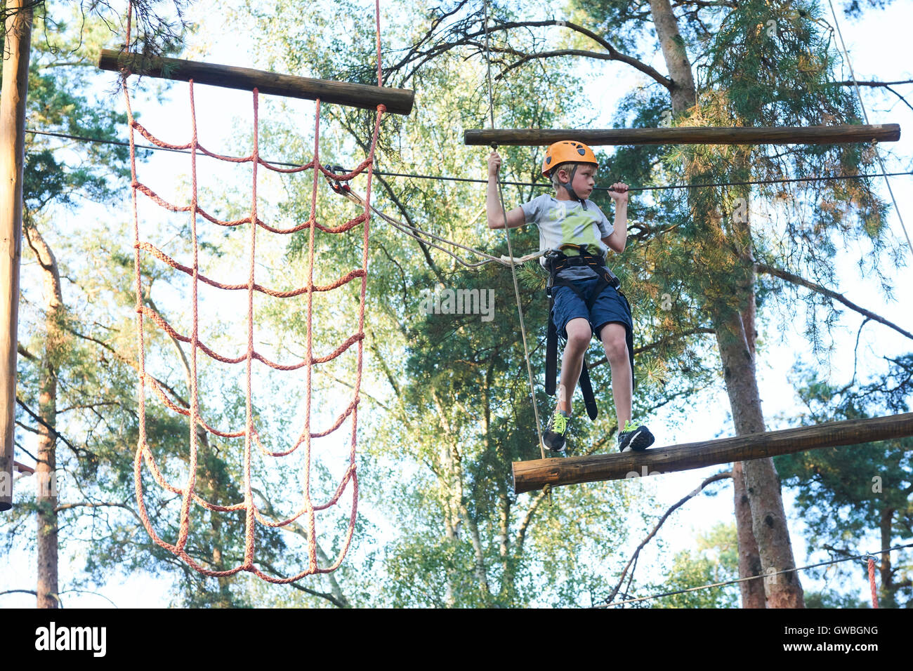 Portrait of active brave boy enjoying outbound climbing at adventure ...