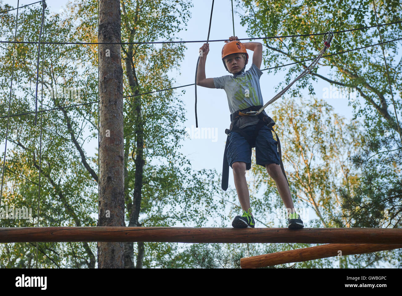 Portrait of active brave boy enjoying outbound climbing at adventure ...