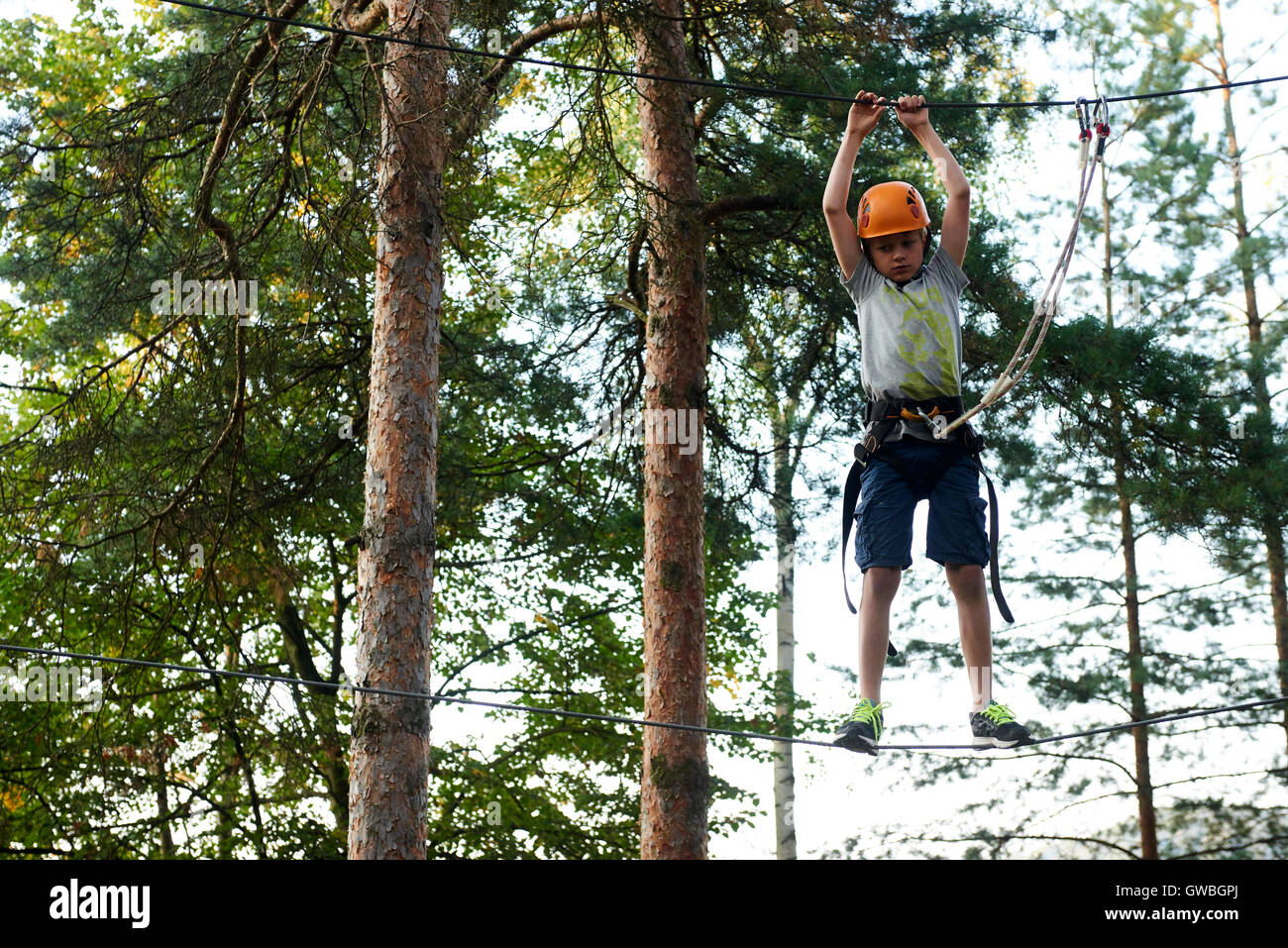 Portrait of active brave boy enjoying outbound climbing at adventure ...