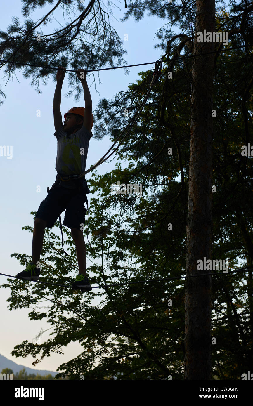 Portrait of active brave boy enjoying outbound climbing at adventure ...