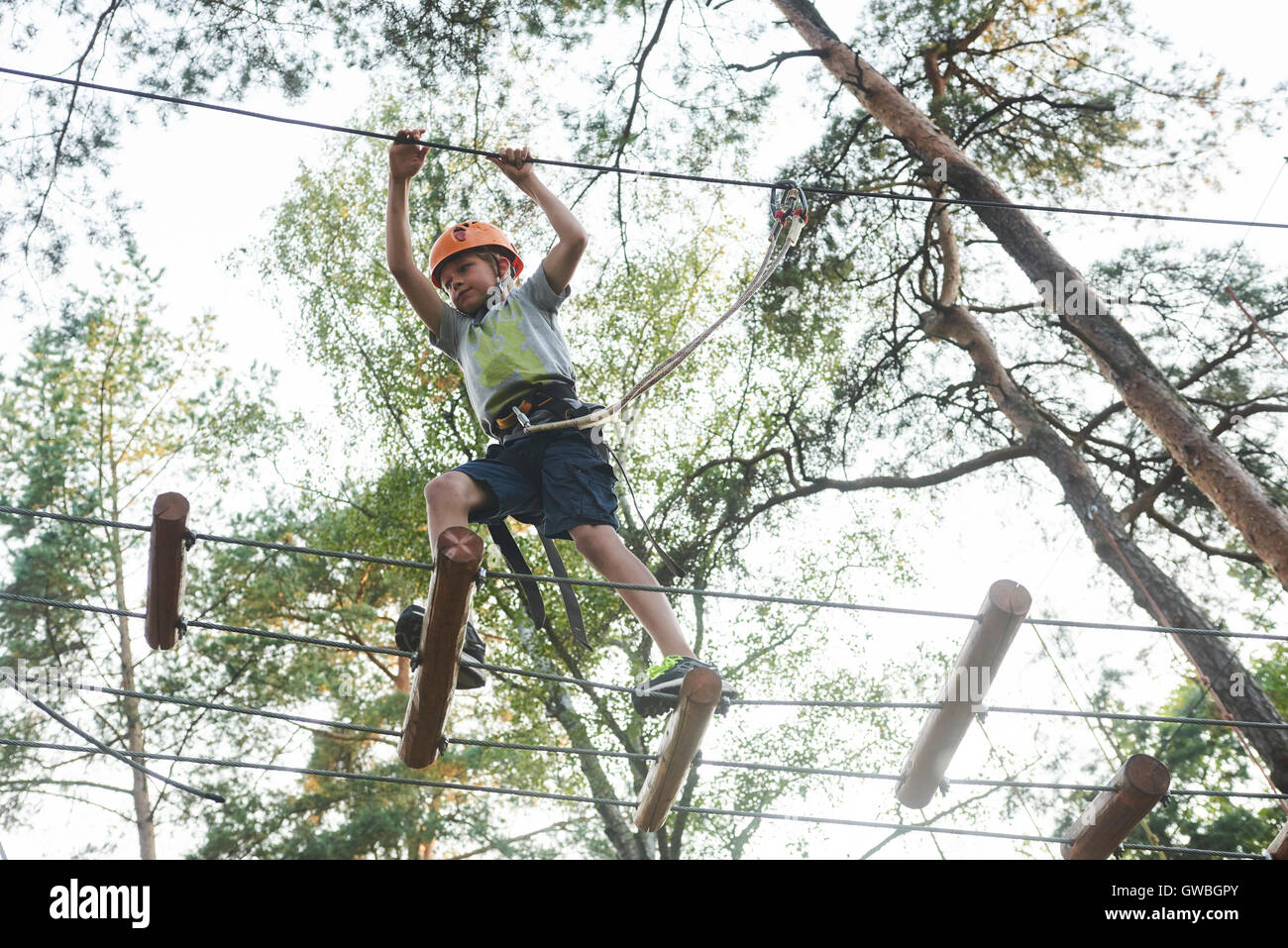 Portrait of active brave boy enjoying outbound climbing at adventure ...