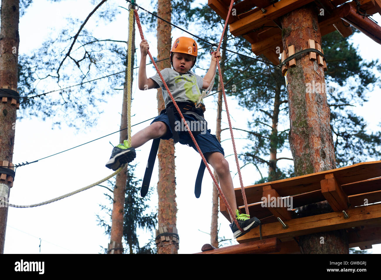 Portrait of active brave boy enjoying outbound climbing at adventure ...