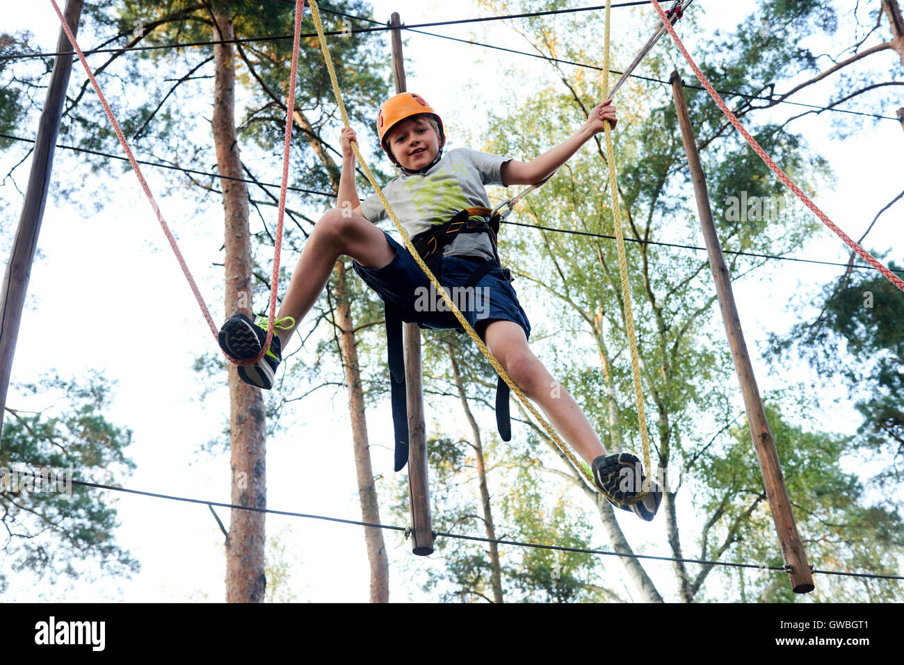 Portrait of active brave boy enjoying outbound climbing at adventure ...