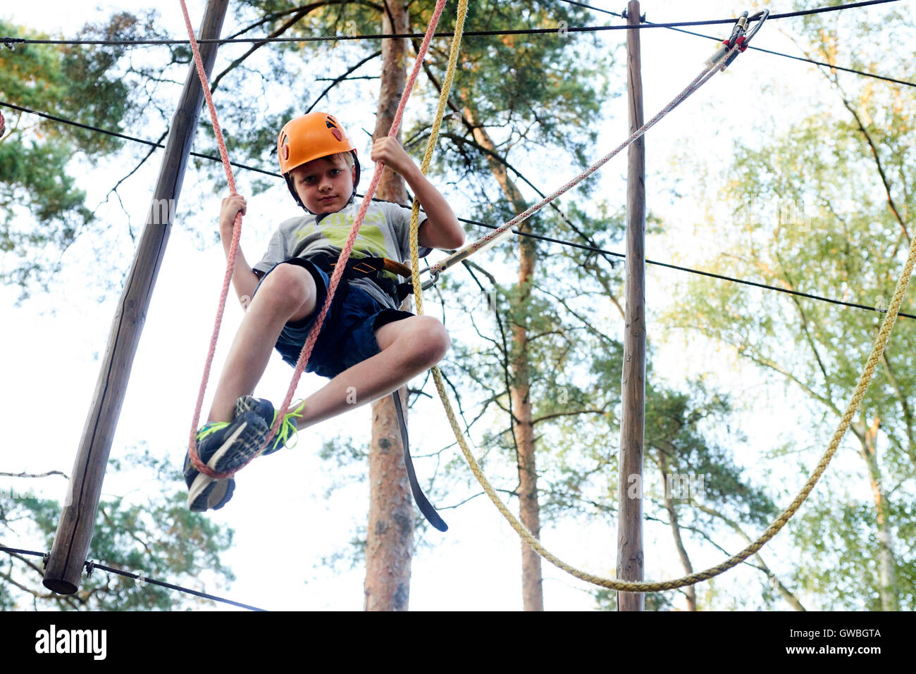 Portrait of active brave boy enjoying outbound climbing at adventure ...