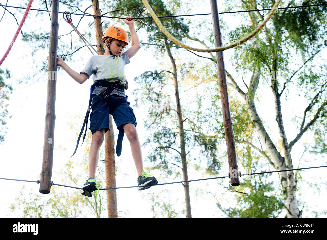 Portrait of active brave boy enjoying outbound climbing at adventure ...
