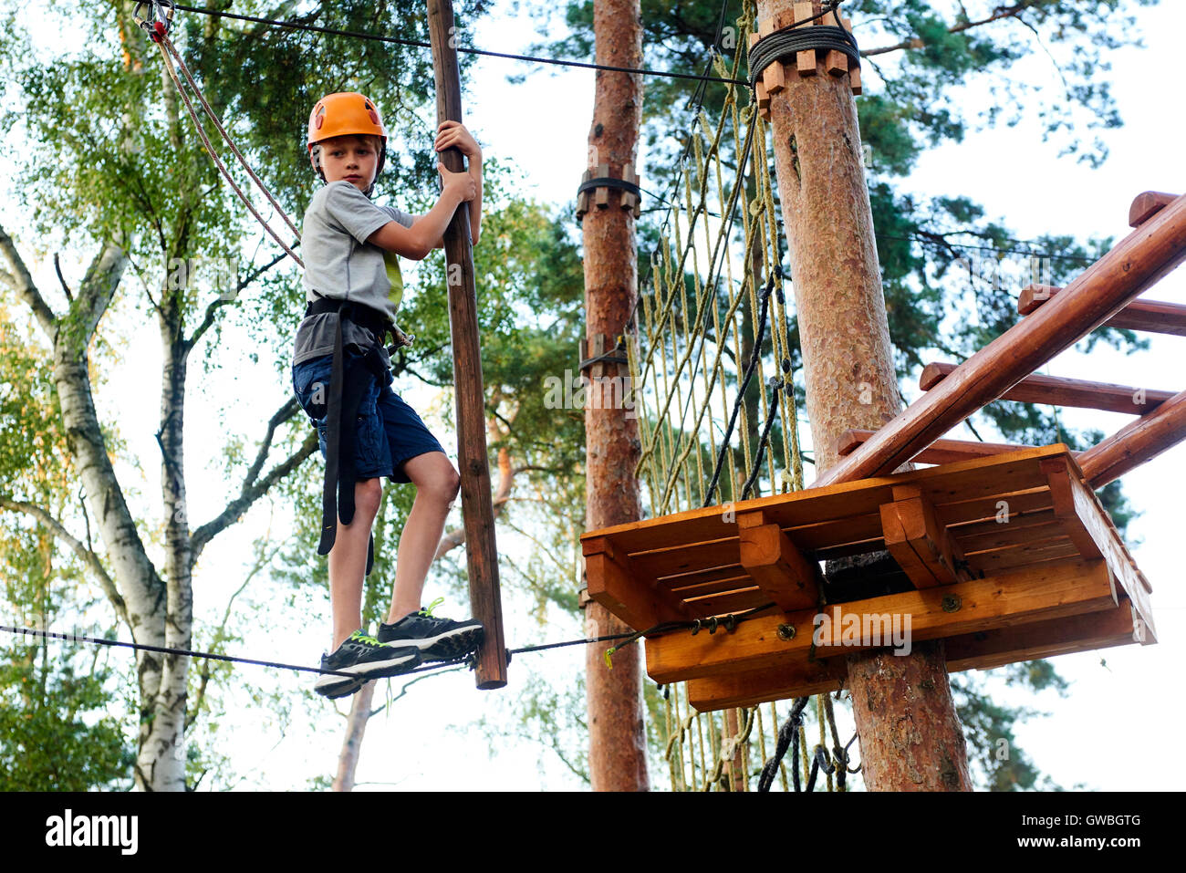 Portrait of active brave boy enjoying outbound climbing at adventure ...