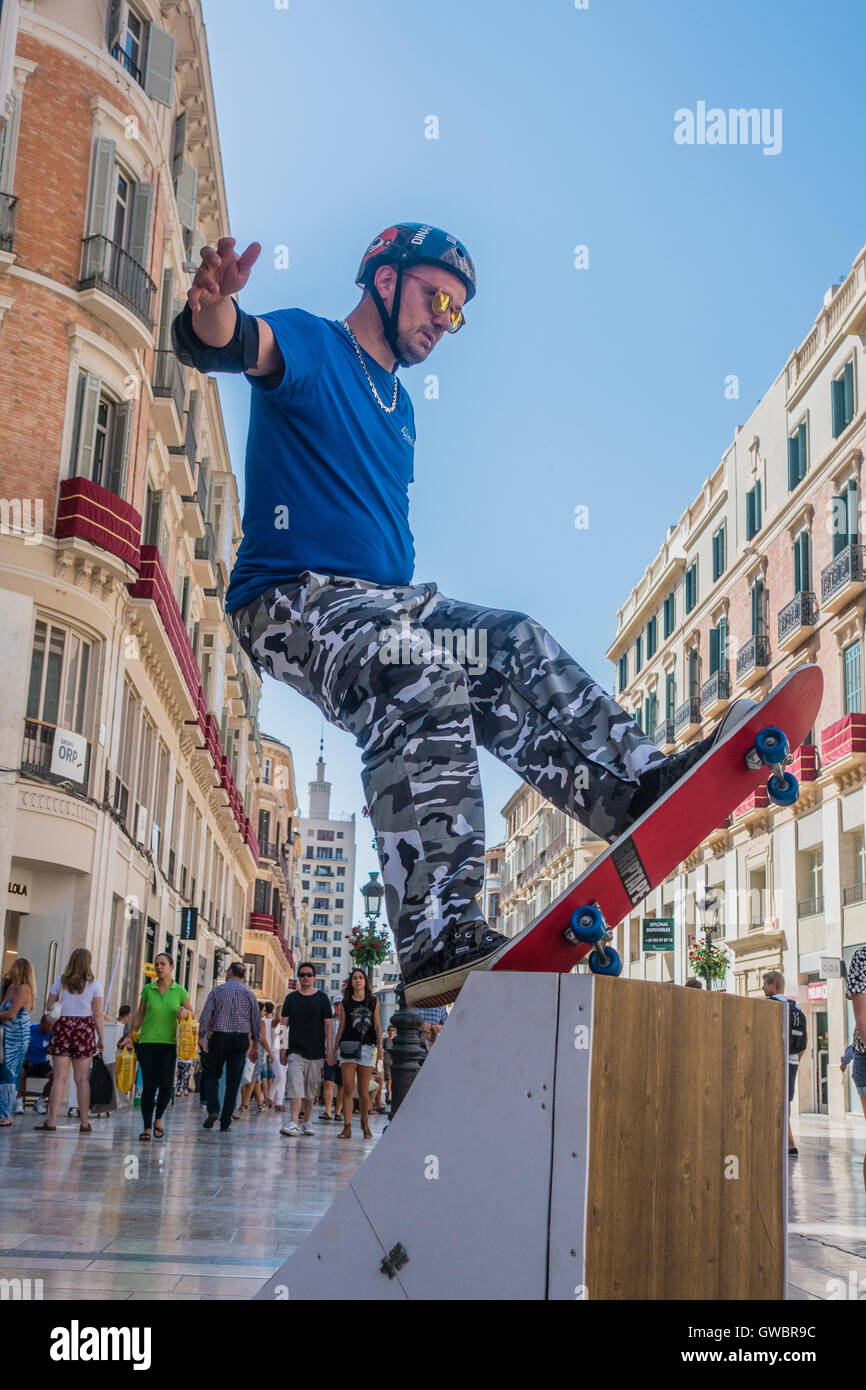 An older male street performer stands on his skateboard which is ...