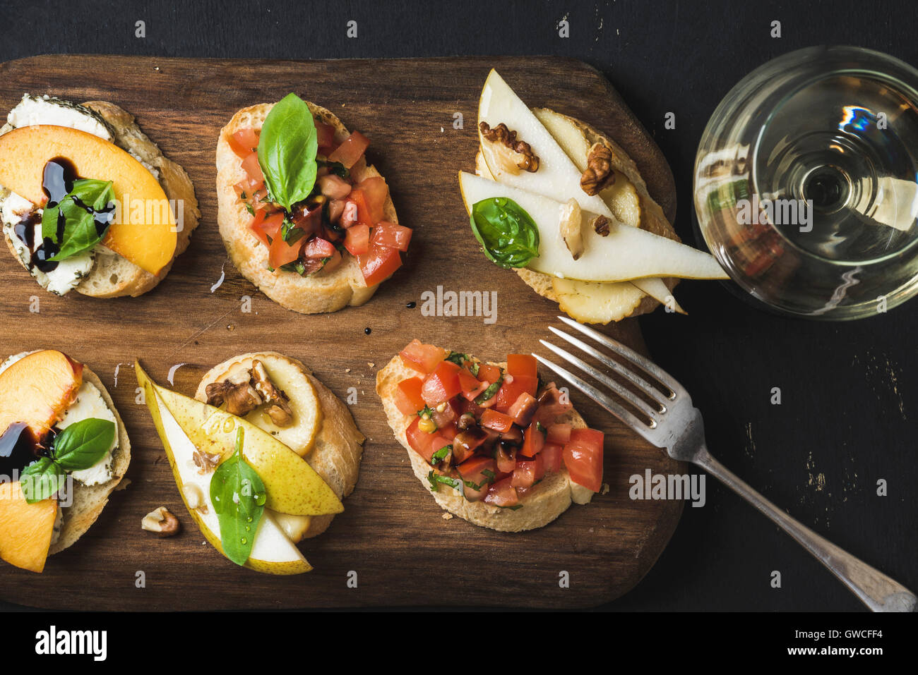 Bruschetta set with various toppings on wooden serving board and glass ...