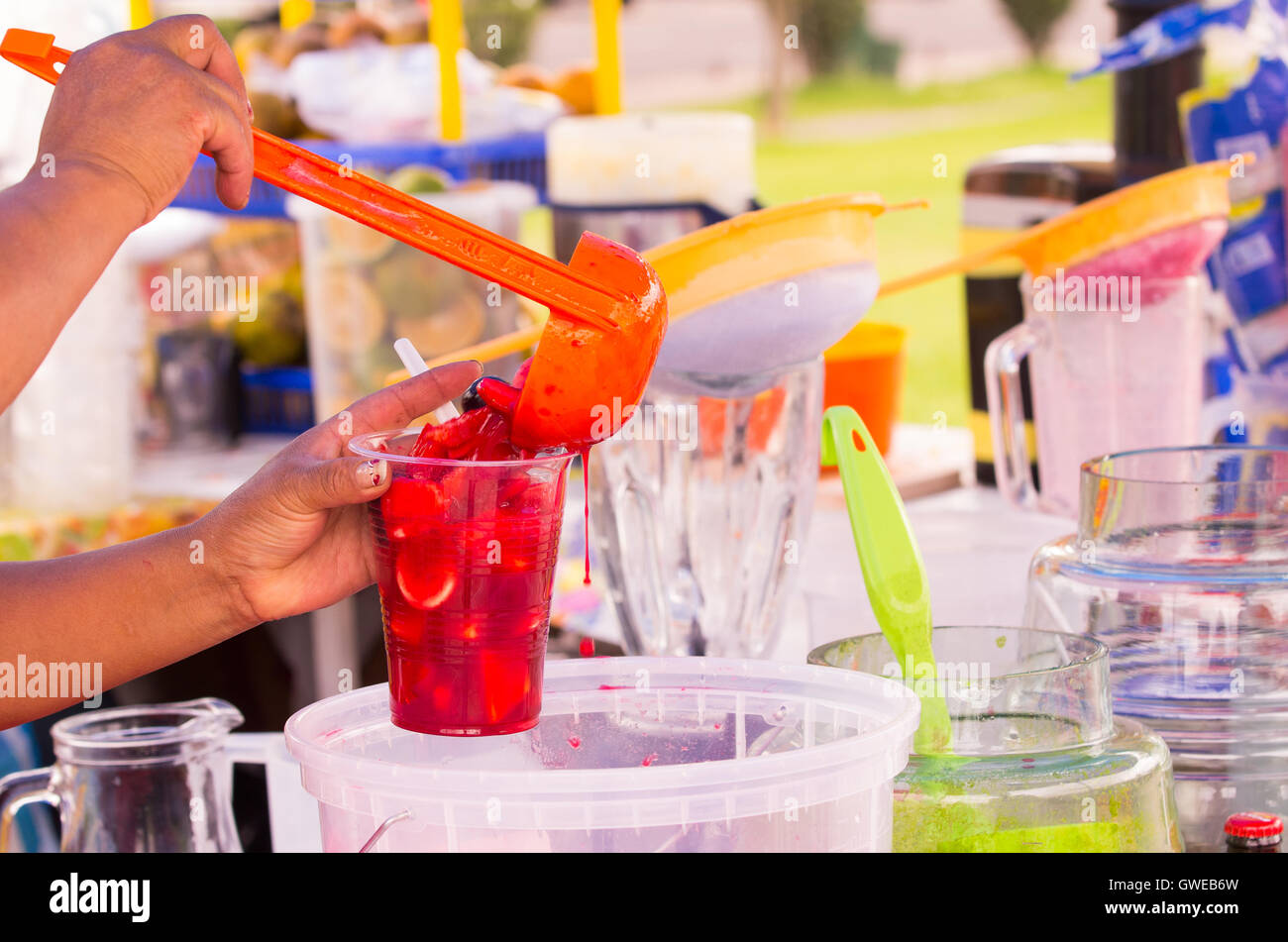 Ladle serving some fruits and juice, traditional from Ecuador. Behind ...