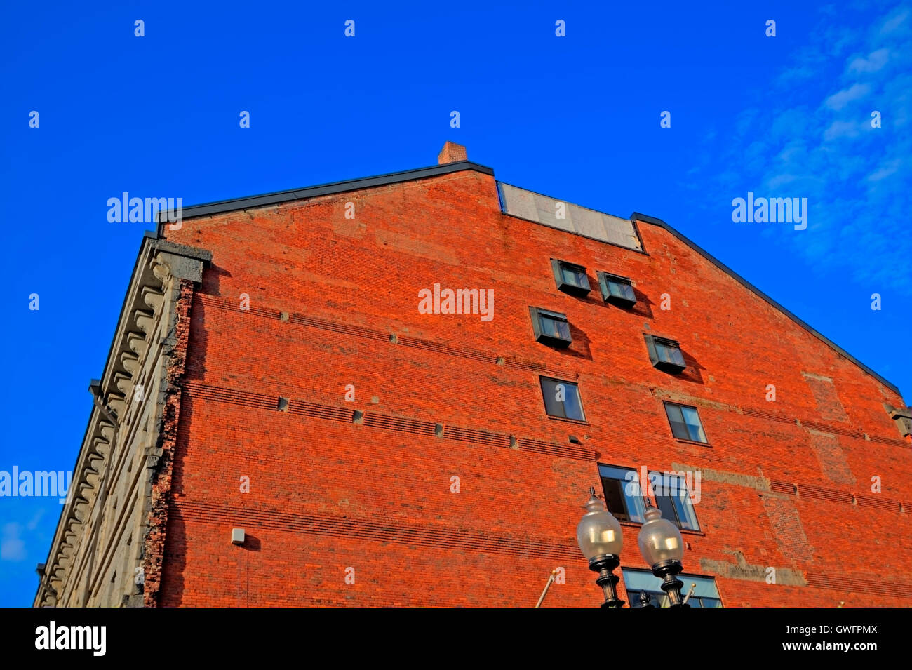 Red brick building wall with windows against the bright blue summer sky ...