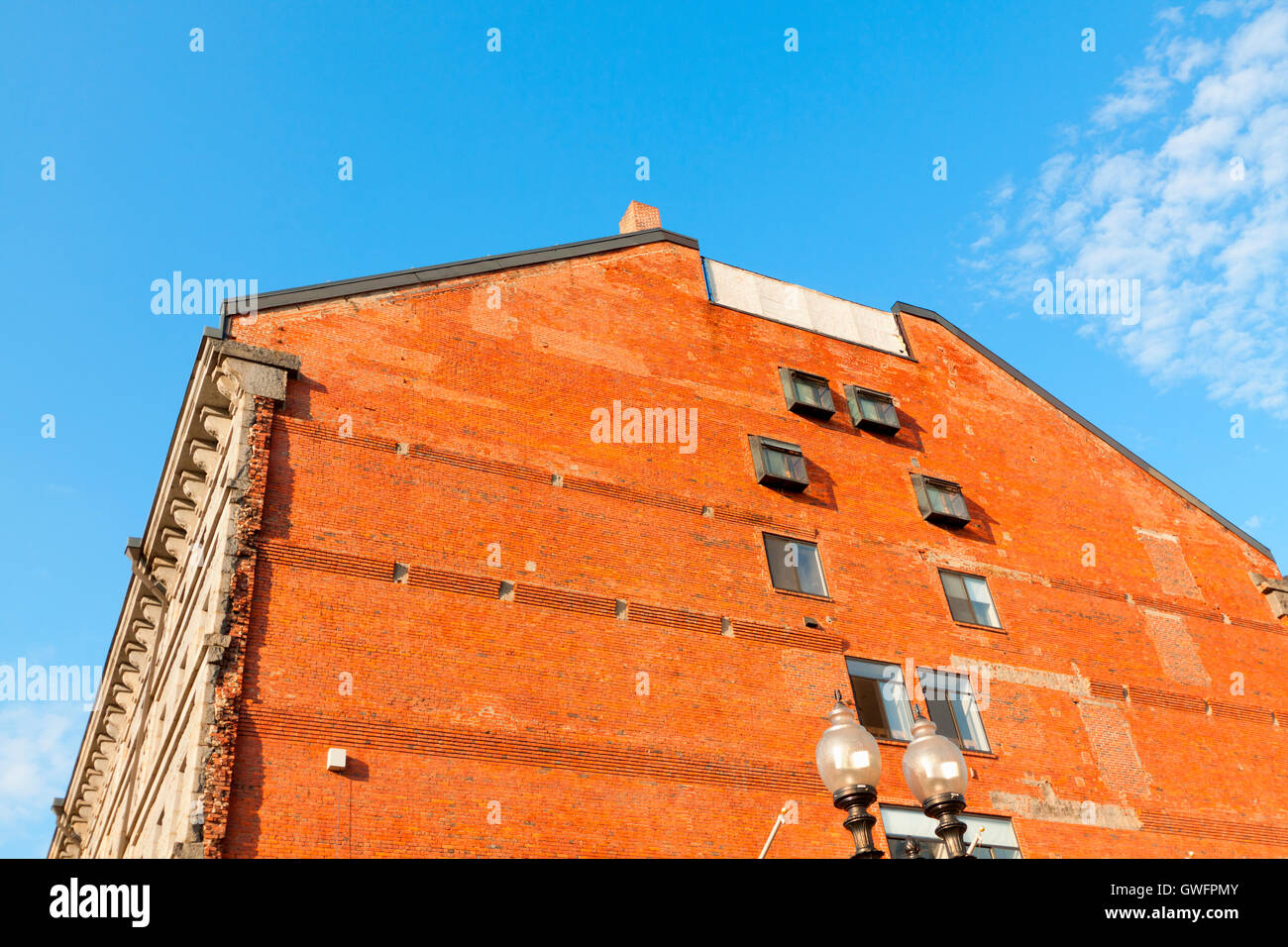 Red brick building wall with windows against the bright blue summer sky ...