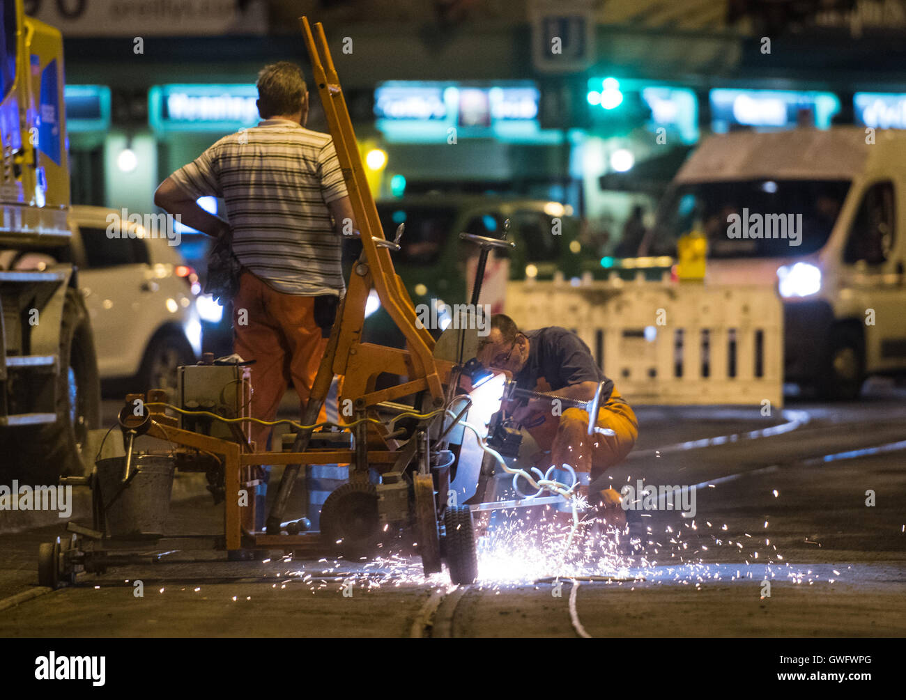 Two construction workers operate a sanding machine on tram tracks in ...