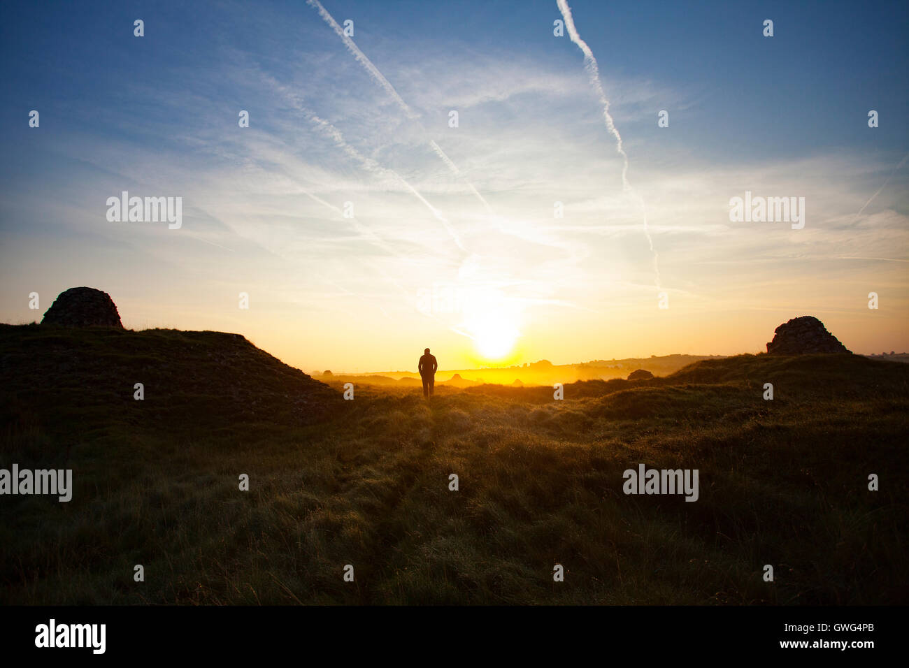 A walker enjoying the sunrise overlooked either side by old lead mine ...
