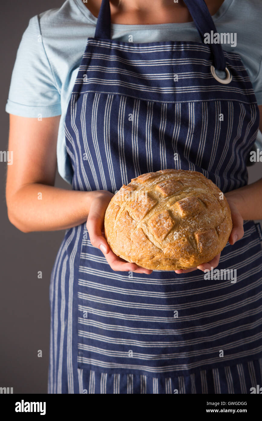 Woman Wearing Apron Holding Freshly Baked Loaf Of Bread Stock Photo - Alamy
