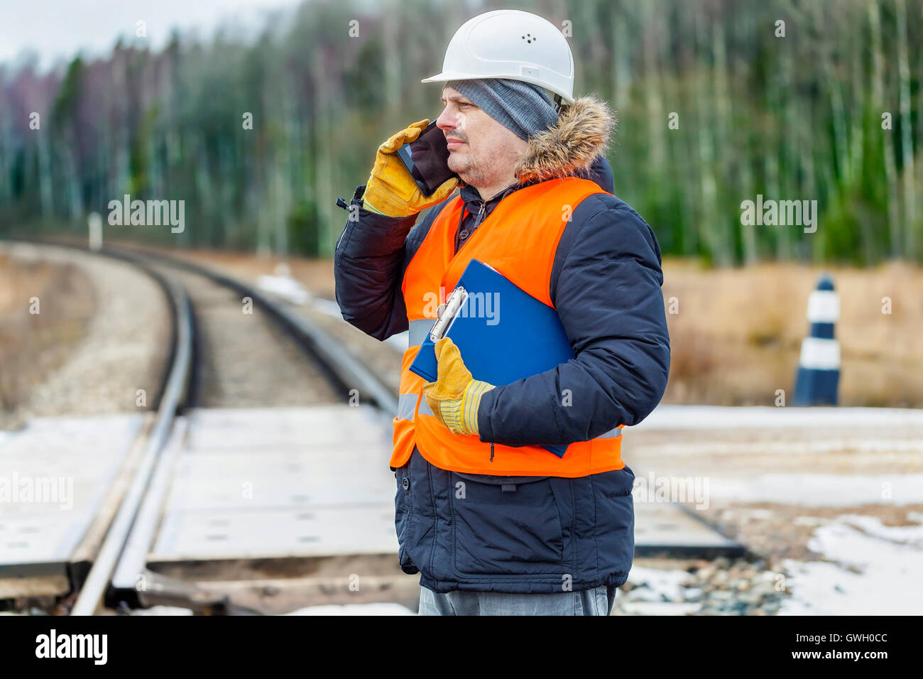 Railroad worker with documentation and smartp hone on railway crossing ...