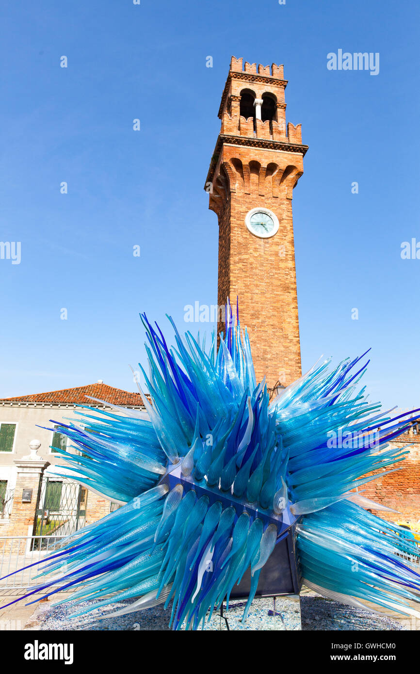 Murano, Italy: A glass sculpture stands before the clock tower ...