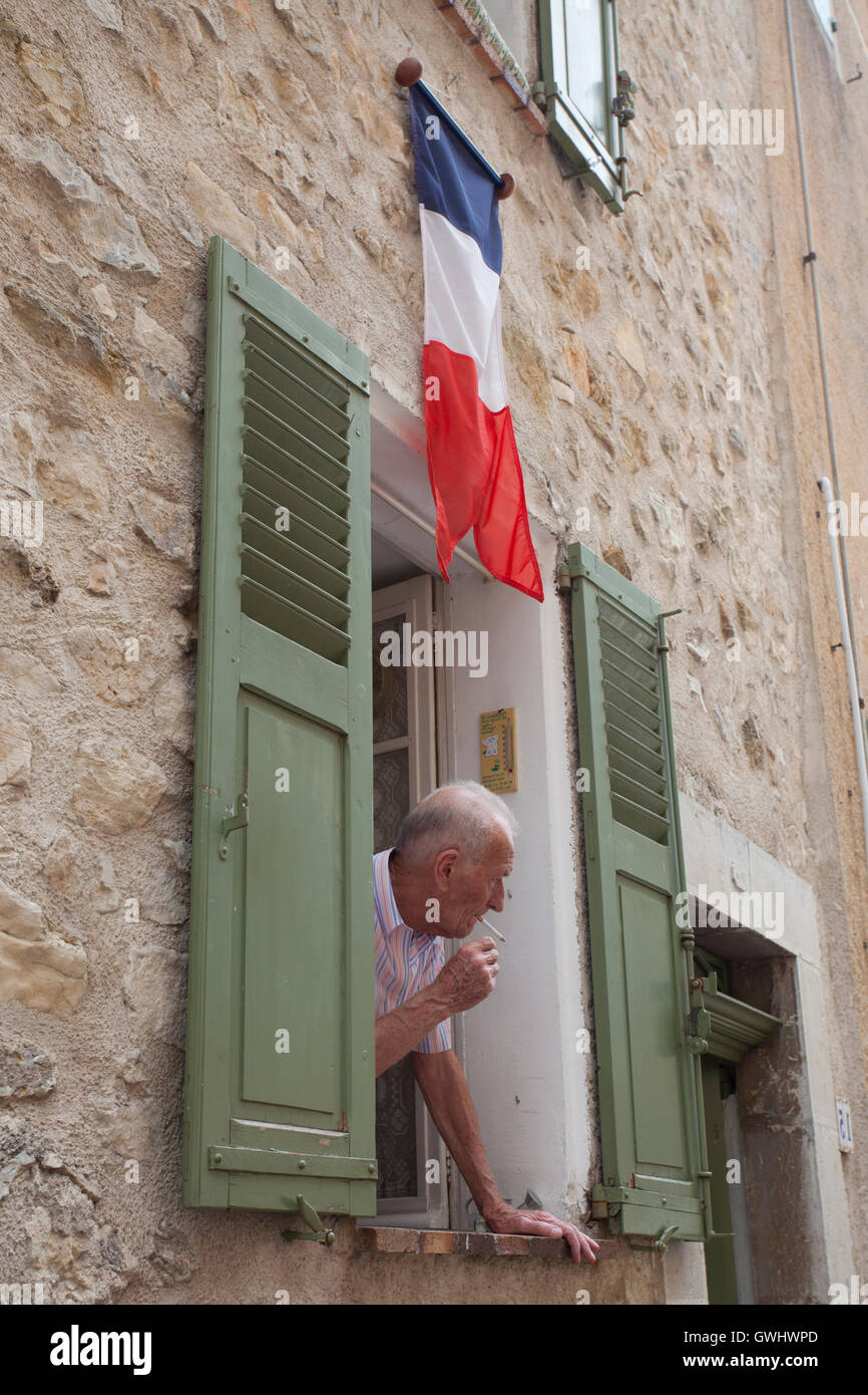 Elderly Frenchman smoking leaning out window Stock Photo - Alamy