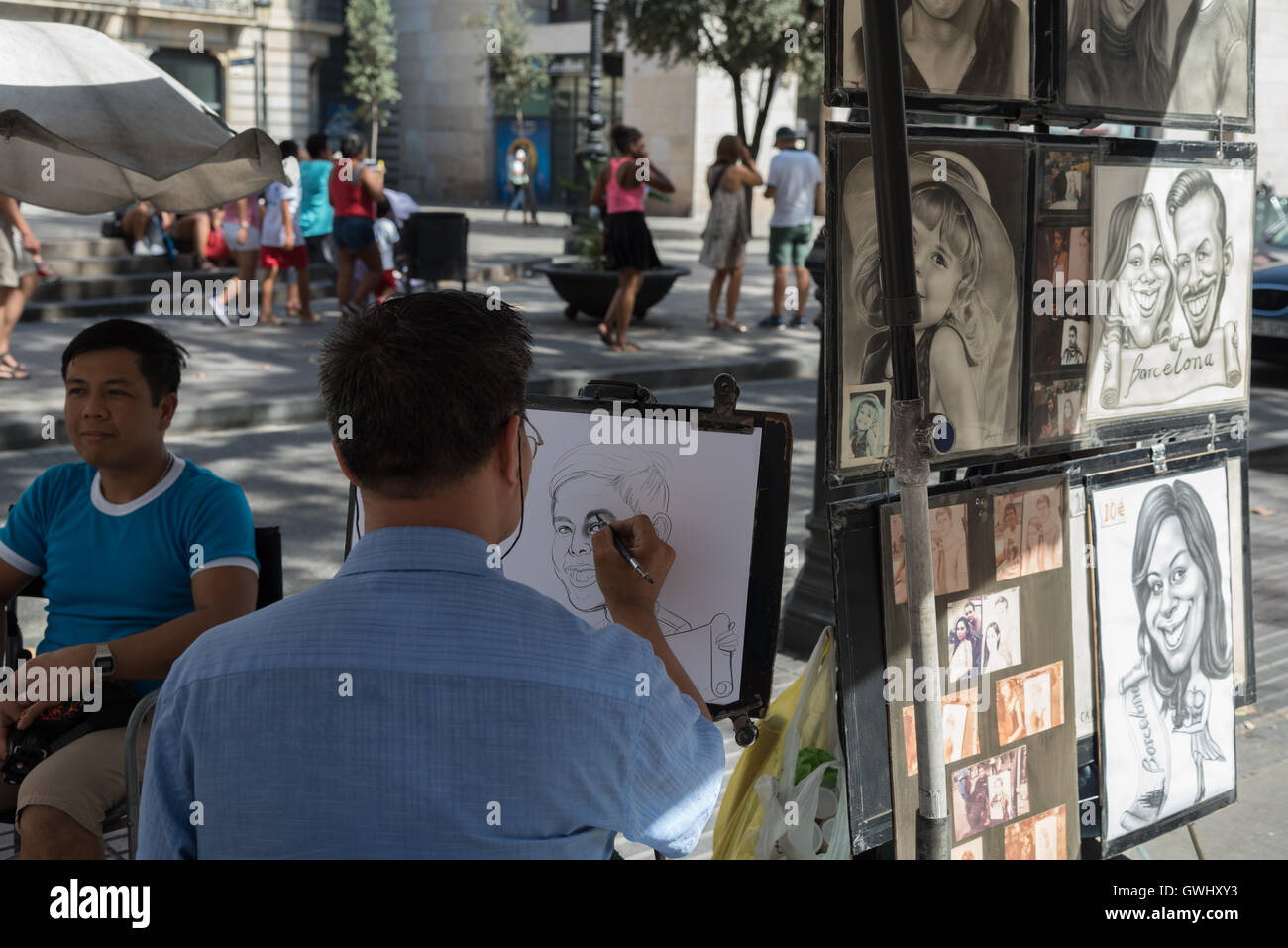 Street artist drawing a caricature of a young man along La Rambla ...