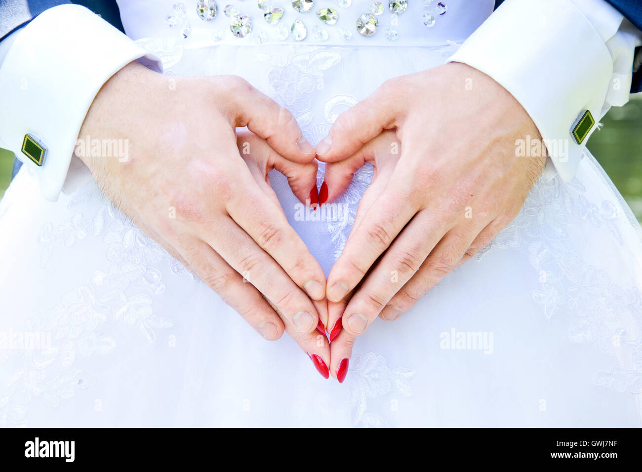 Bride and groom hold hands in love heart shape. Marriage and wedding ...