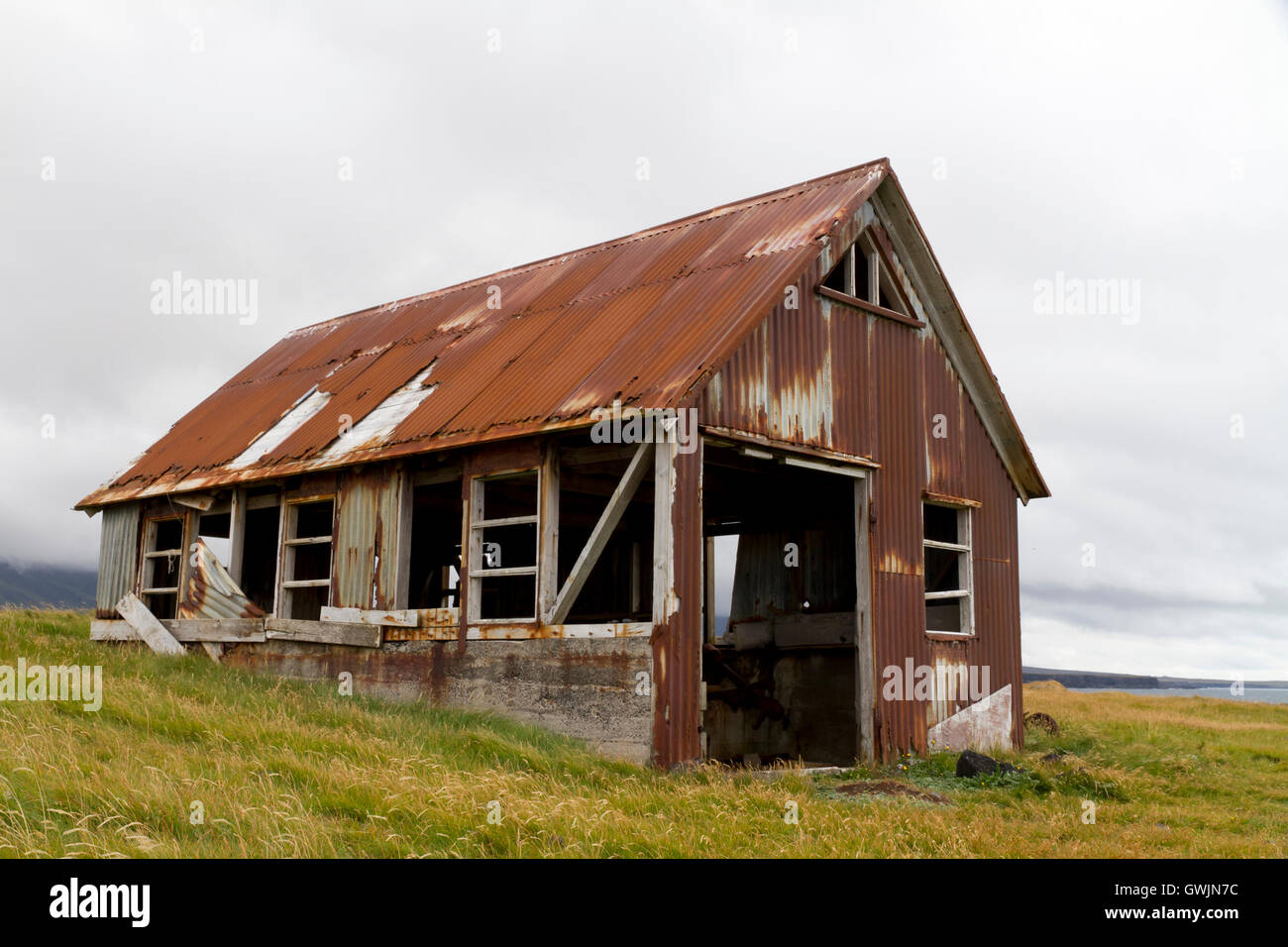 Run down old shed clad in rusty corrugated iron, situated on the coast ...