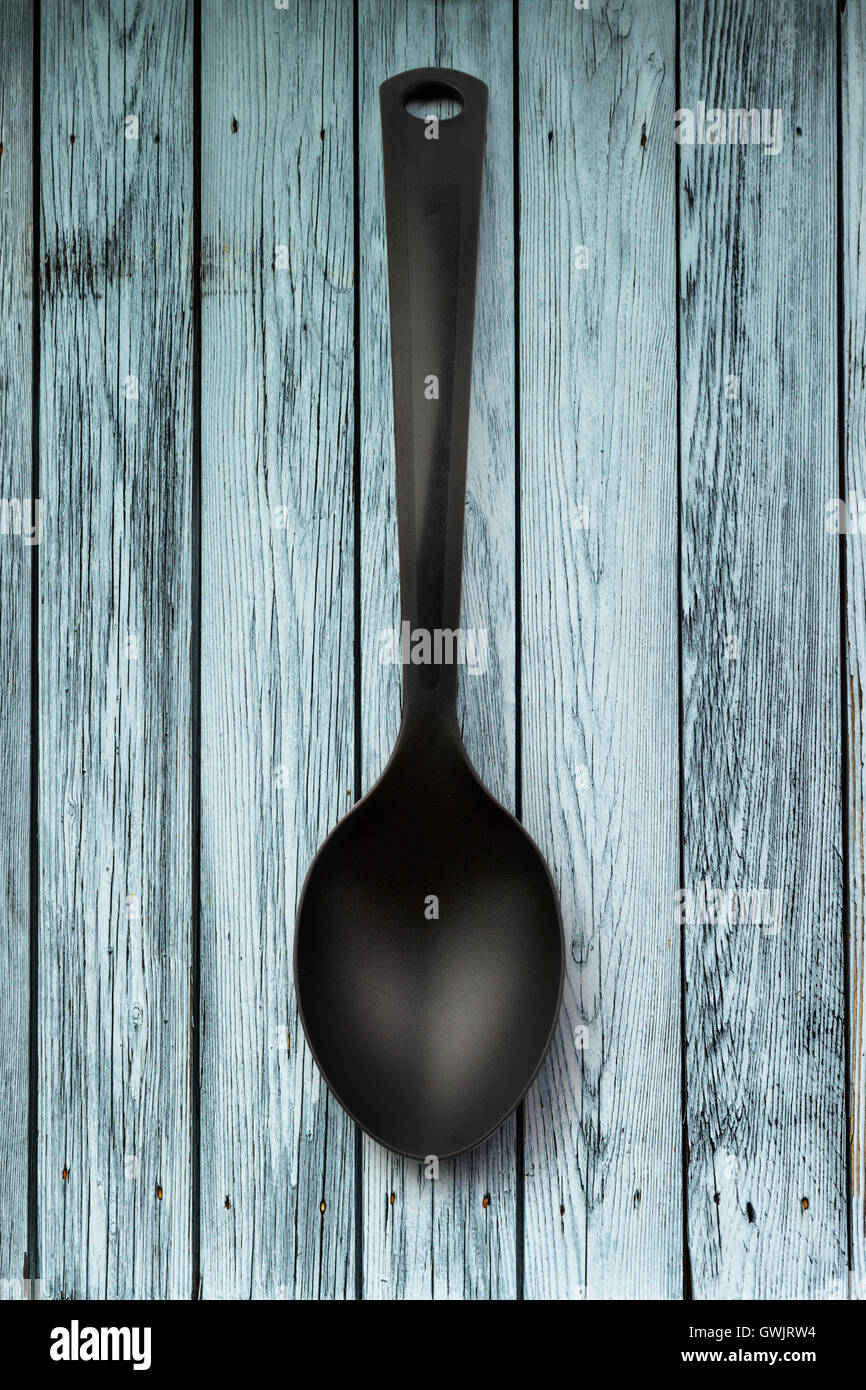 Black spoon on wooden panel background closeup Stock Photo - Alamy