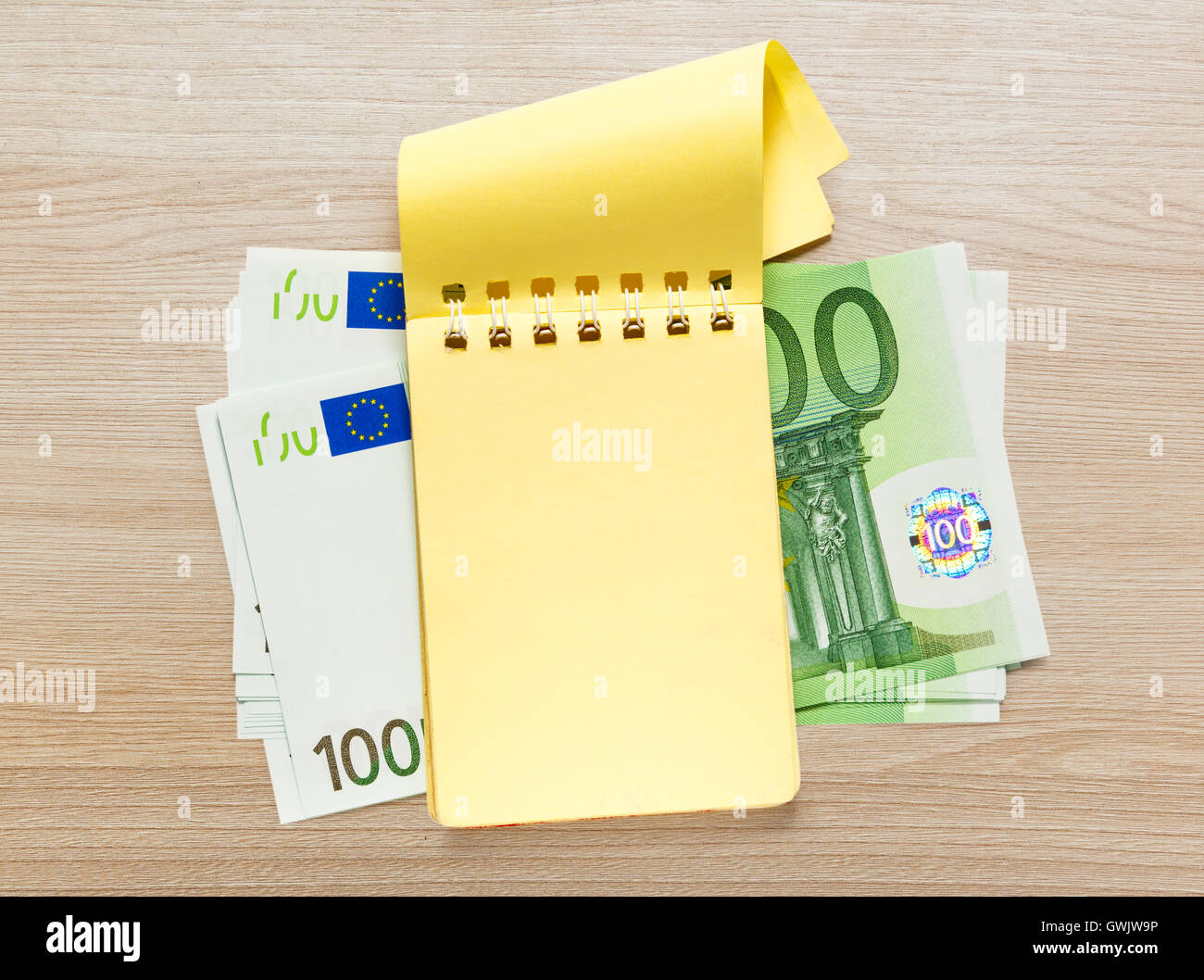One hundred euro banknotes and blank yellow notepad Stock Photo - Alamy