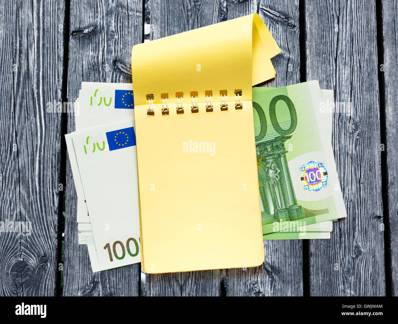 One hundred euro banknotes and blank yellow notepad Stock Photo - Alamy