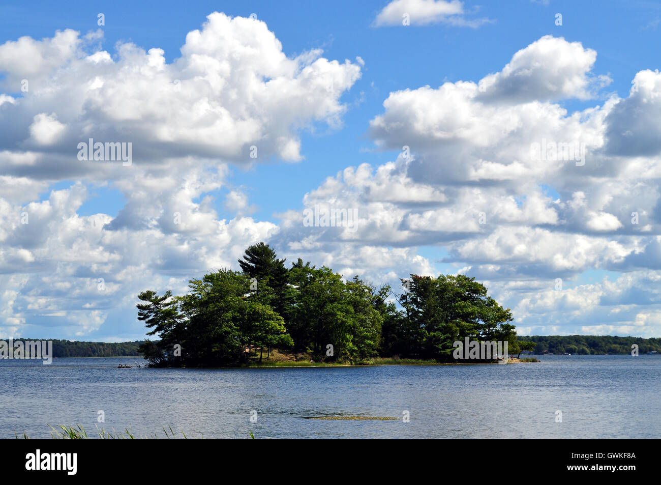 A small island surrounded by water and blue skies Stock Photo - Alamy