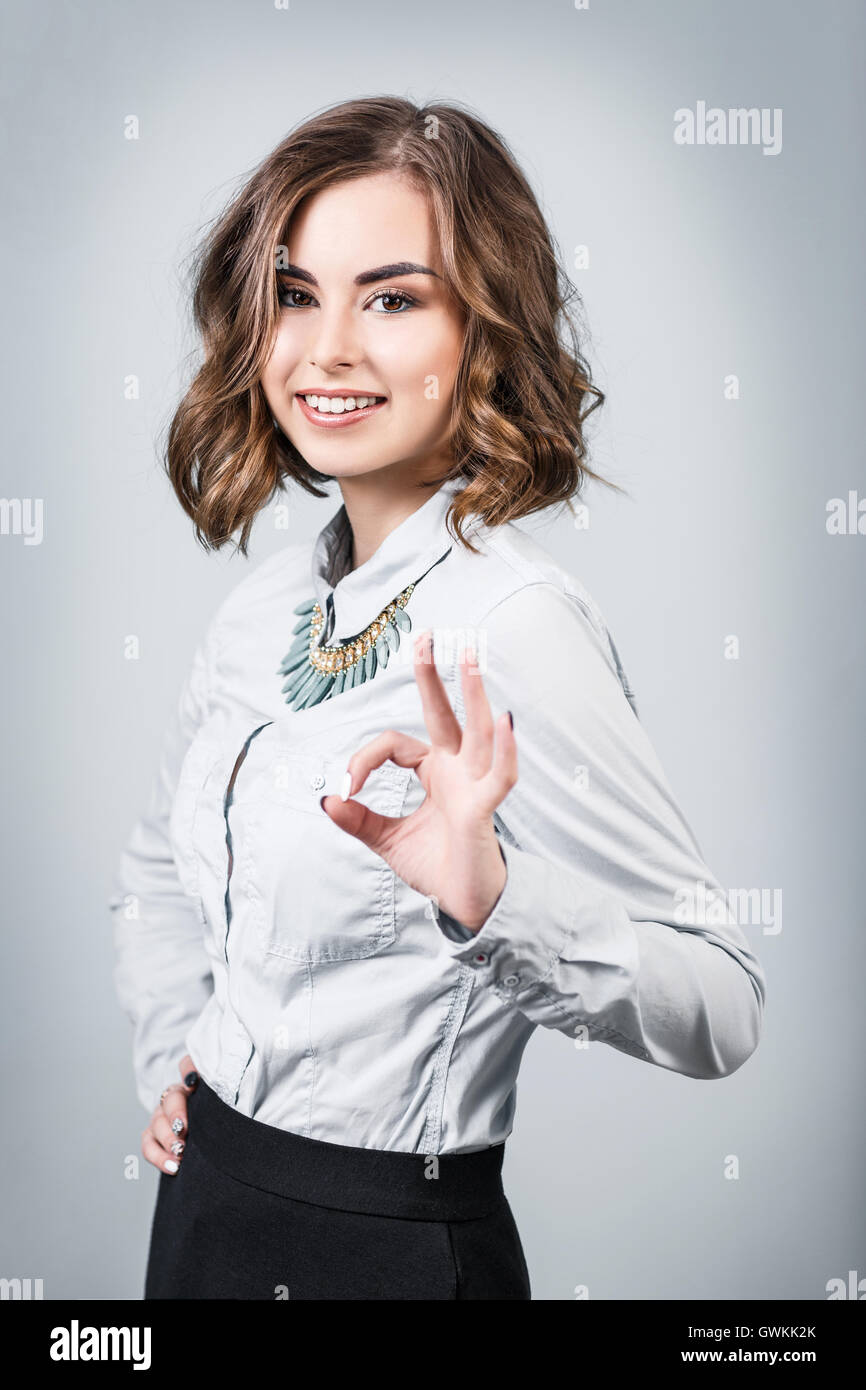 Beautiful woman showing OK sign on the gray background Stock Photo - Alamy