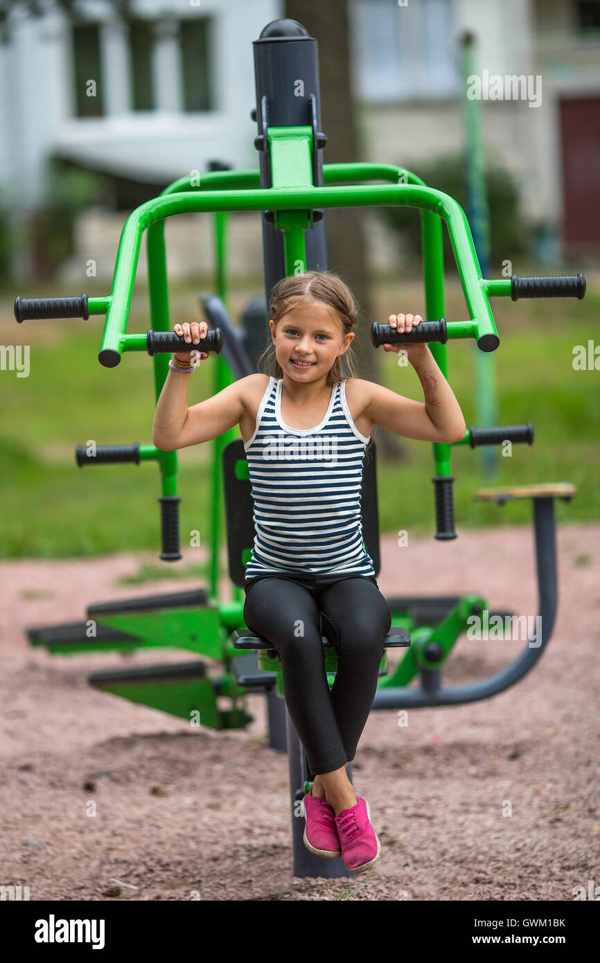Little girl is engaged in sport fitness equipment outdoor Stock Photo ...