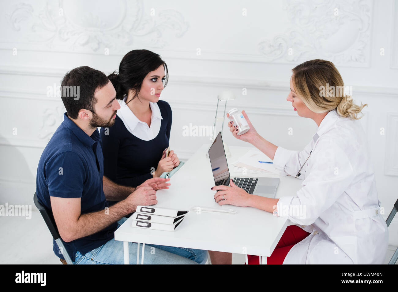 Happy Young Couple Giving Envelope To Female Doctor Stock Photo - Alamy