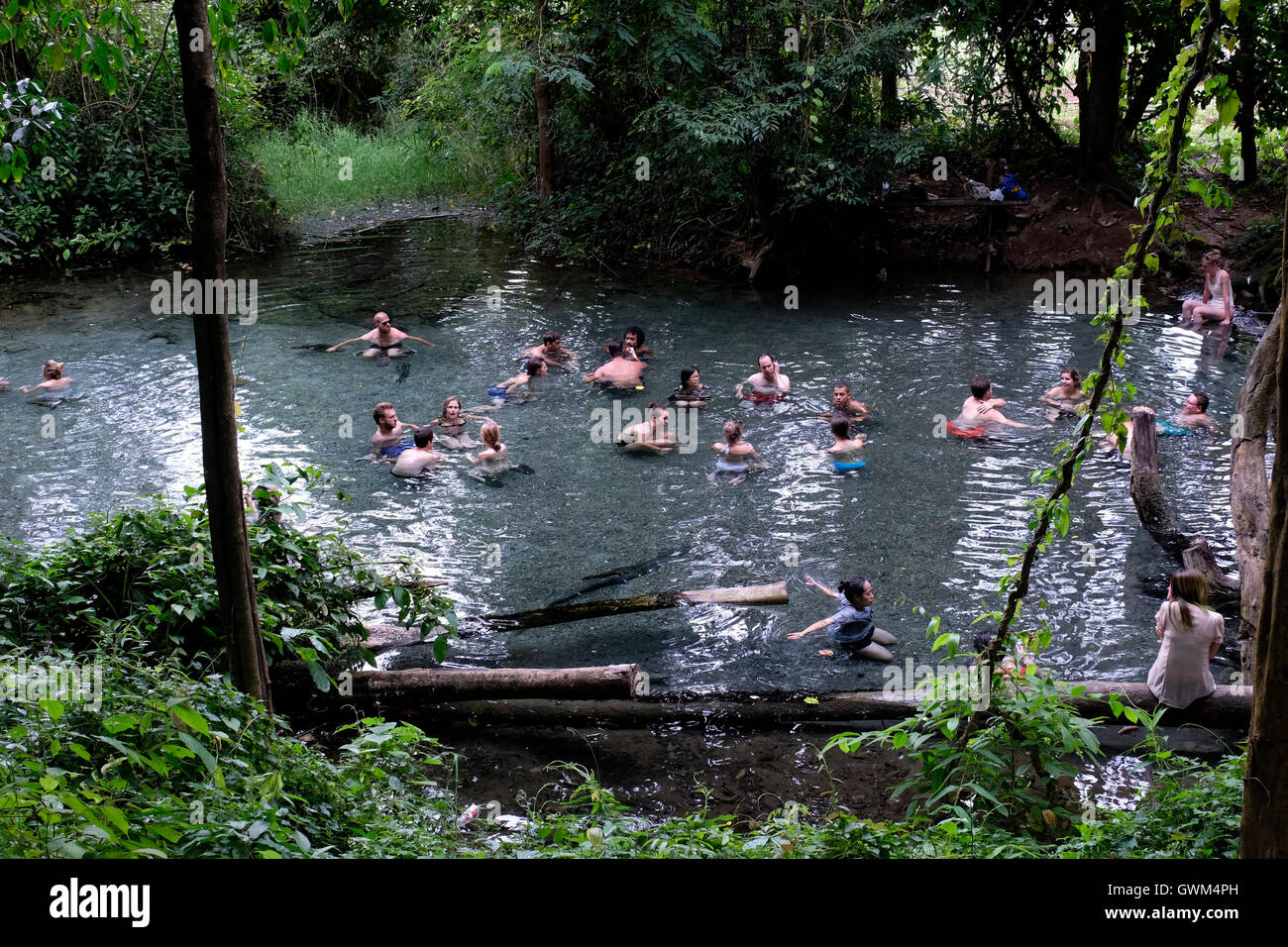 Tourists bathing in the shallow lagoon of Sai Ngam Hot Springs ...
