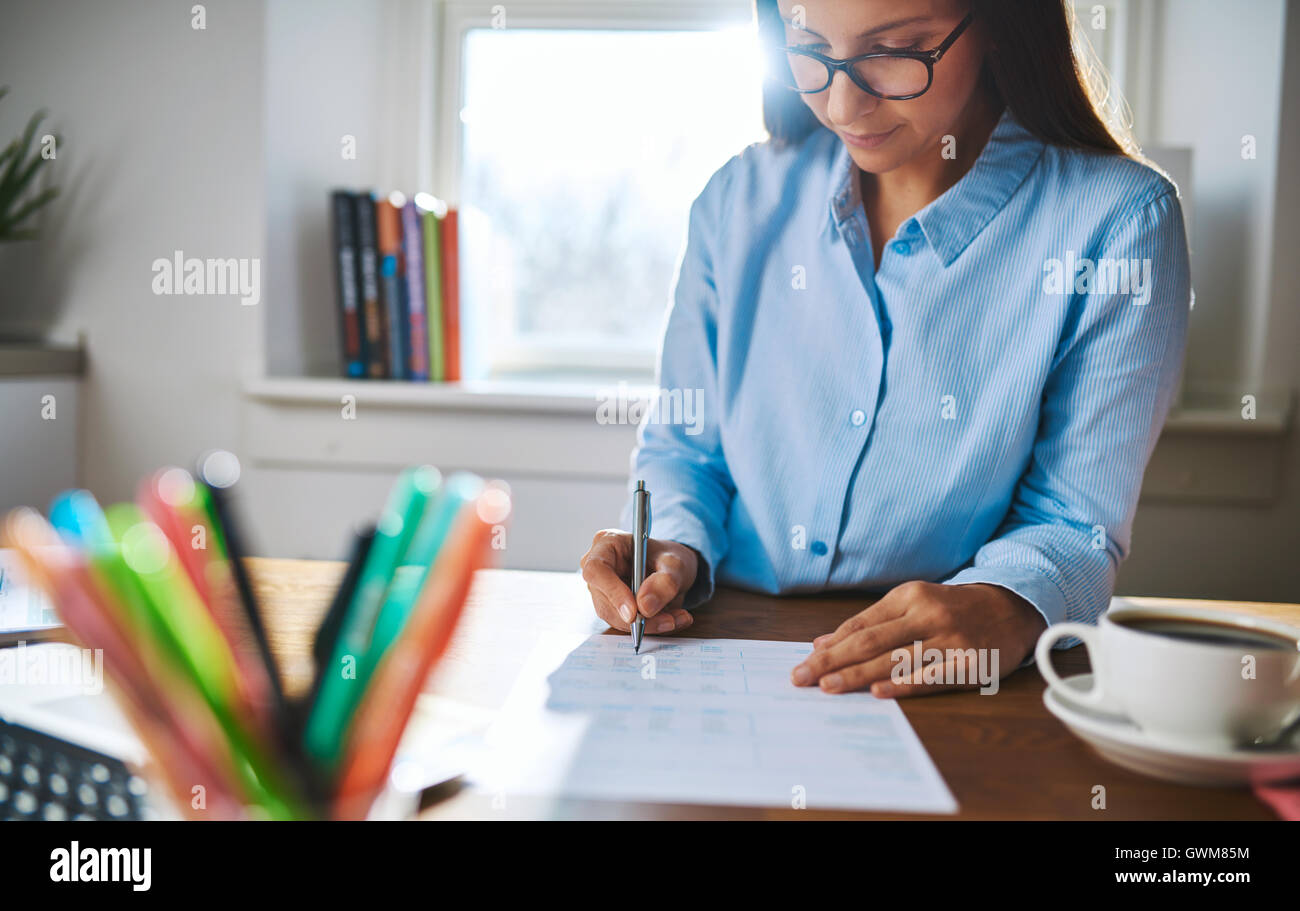 Young businesswoman busy writing notes or a report as she sits at her ...