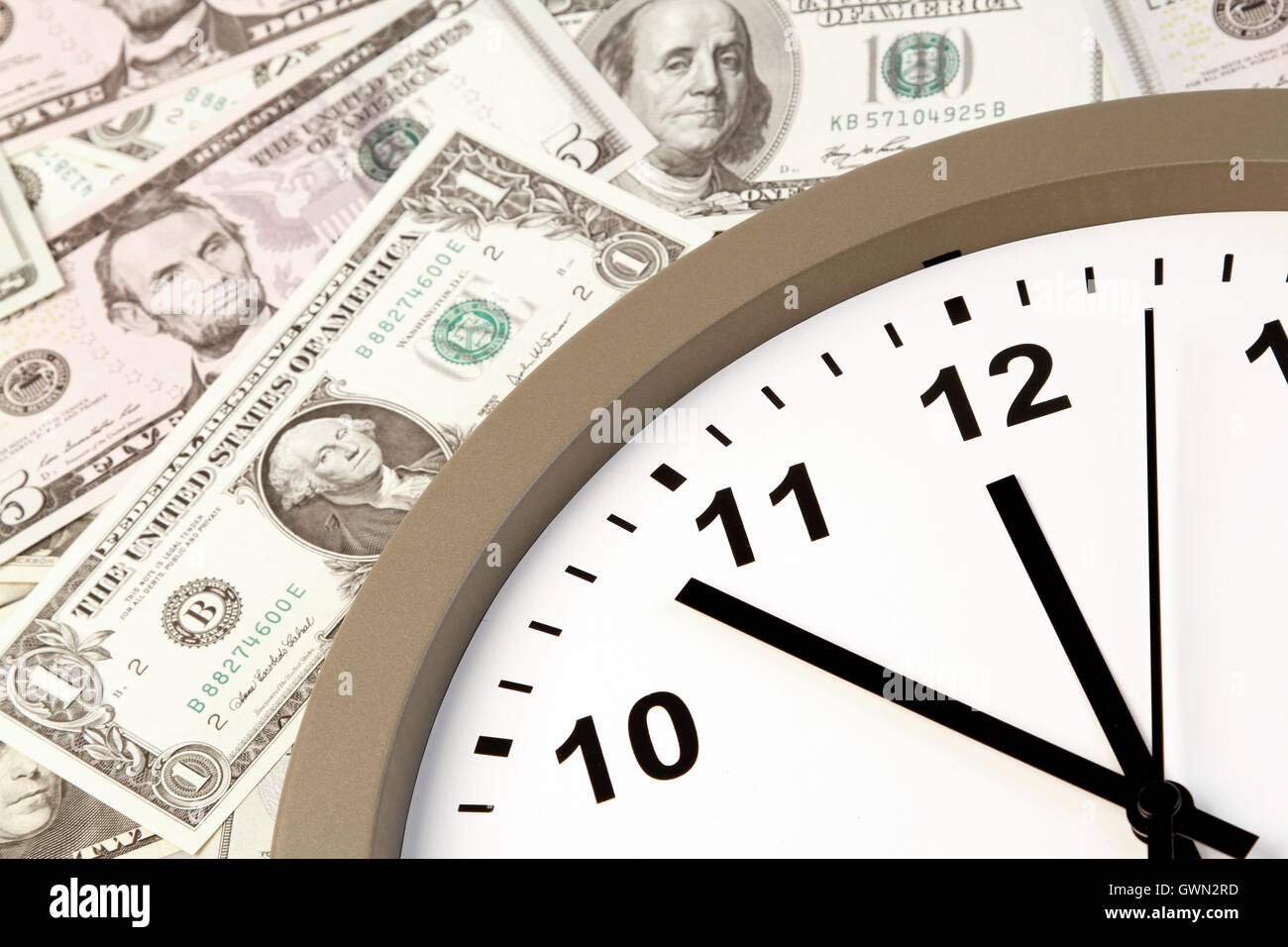 Clock on assorted American banknotes. Time is money idea Stock Photo ...