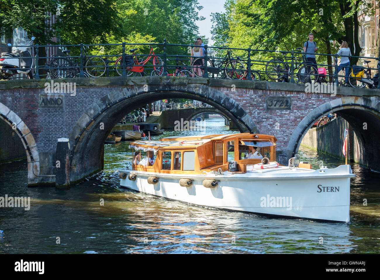 Salon boat Stern passes under a bridge over an Amsterdam canal into ...