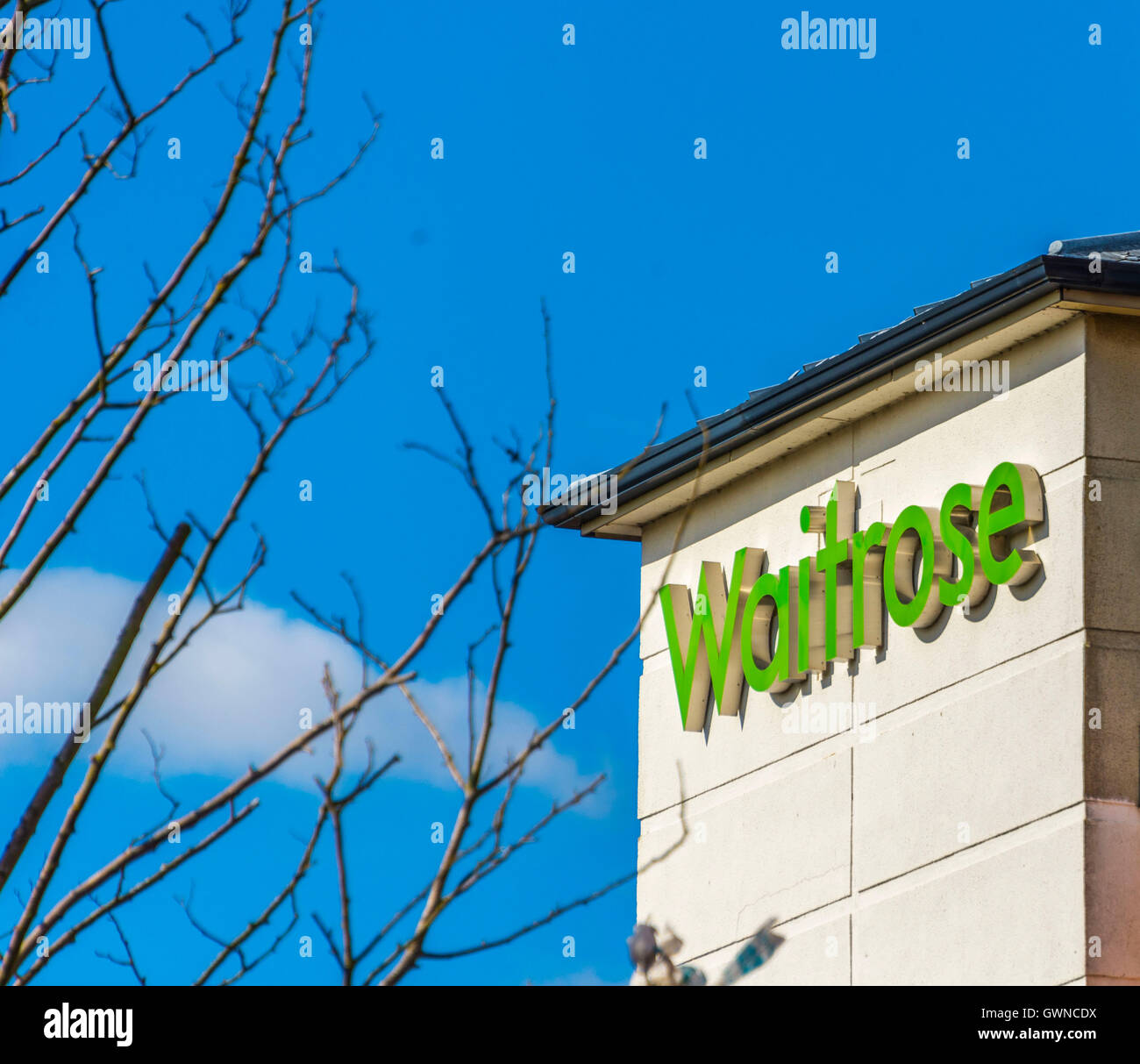 Waitrose supermarket sign large green on building wall with blue sky ...